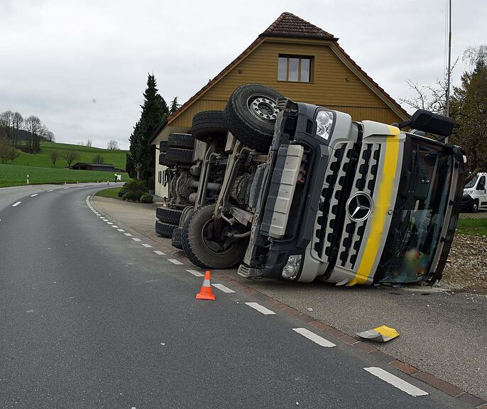 Lastwagen kippt um und prallt gegen Gebäude