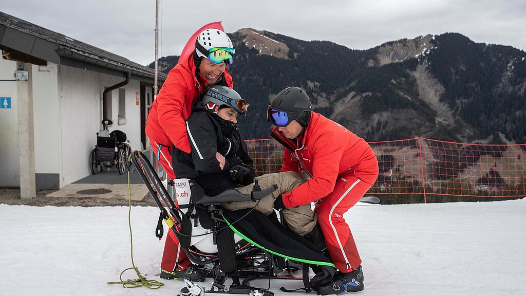 Skilehrer Richard Studer (links) und ein Kollege heben Peter Zihlmann ...